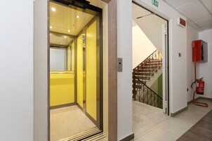 Um corredor com elevador, escada e extintor de incêndio.