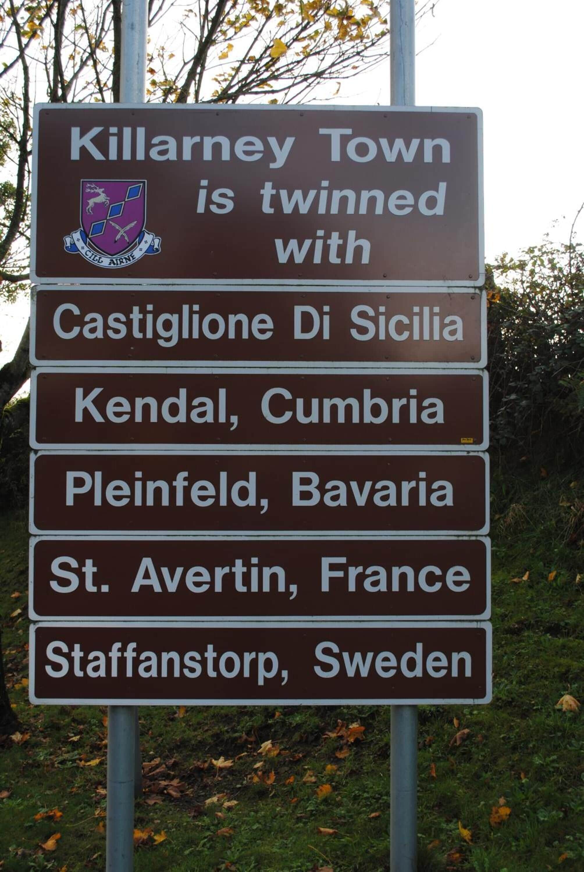 Placa listando cidades gêmeas de Killarney: Castiglione Di Sicilia, Kendall, Cumbria, Pleinfeld, Baviera, St. Aventin, França, e Staffanstorp, Suécia.
