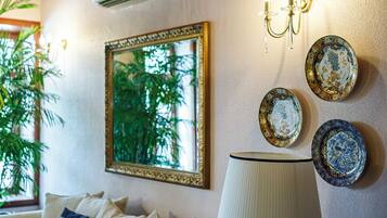 Uma sala de estar acolhedora com sofá, luminária decorativa, pratos pendurados na parede e uma moldura com fotografia.