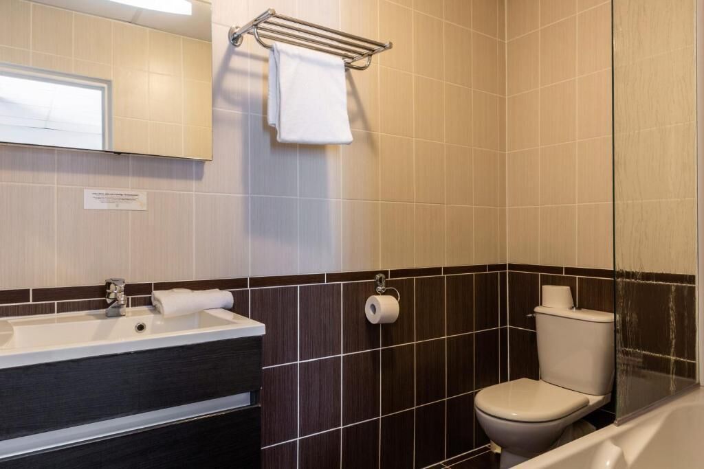 Casa de banho com lavatório, espelho, porta-toalhas, sanita e banheira.