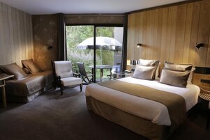 Quarto de hotel com uma cama grande, um sofá, uma cadeira e uma mesa com guarda-sol.