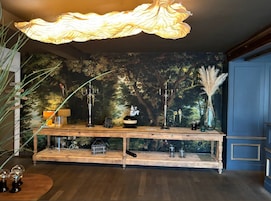 Um balcão de madeira com design rústico, apresentando um candelabro, vasos decorativos e um painel com tema de floresta.