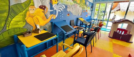 Uma área de recreação infantil com mobiliário colorido e um mural de animais.