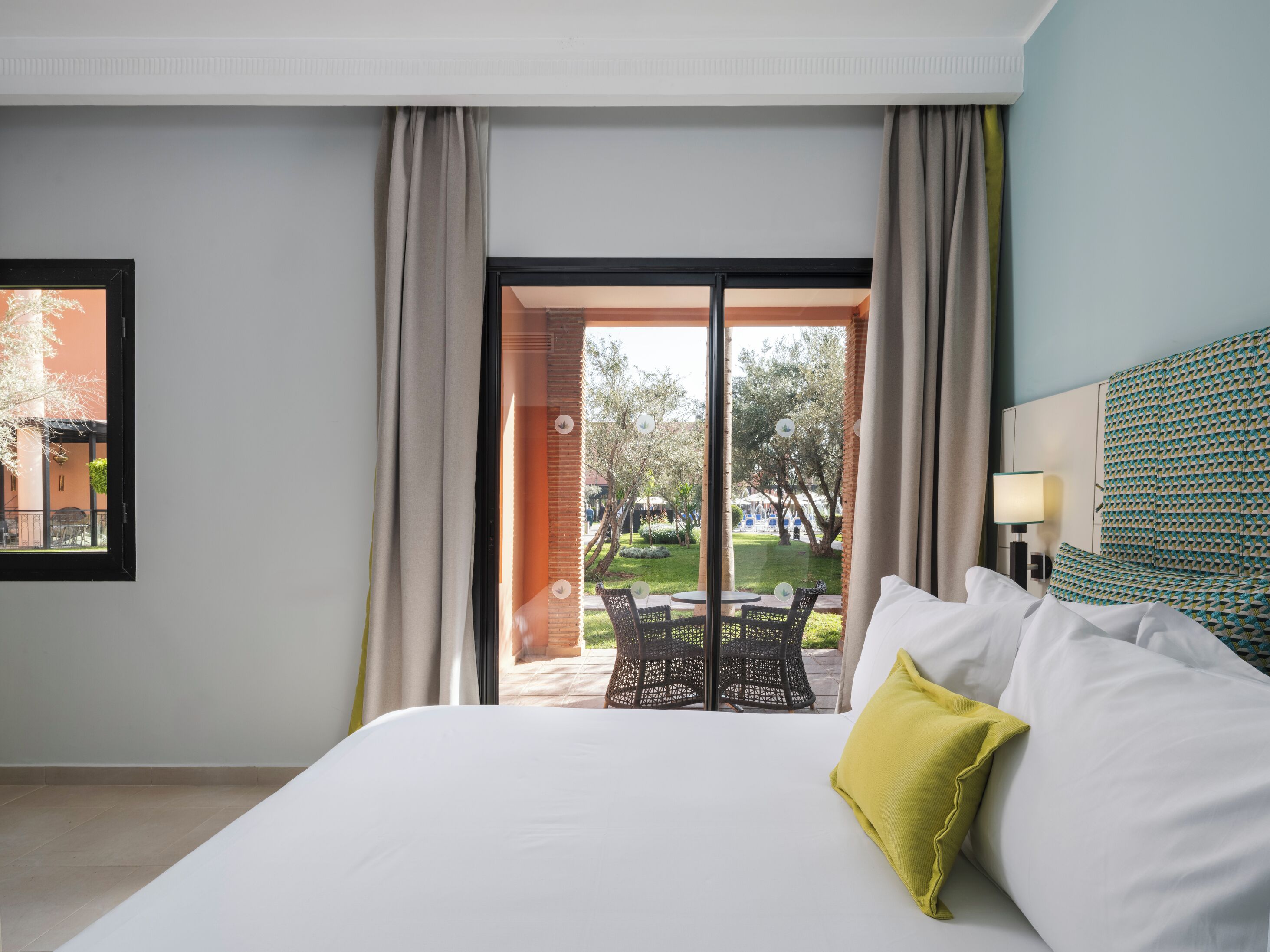 Quarto de hotel com cama, vista para o pátio e área de refeições.