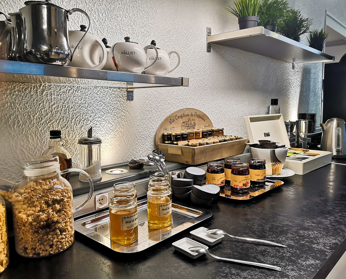 Uma bancada de cozinha com vários potes de mel, uma cafeteira e um conjunto de chá.