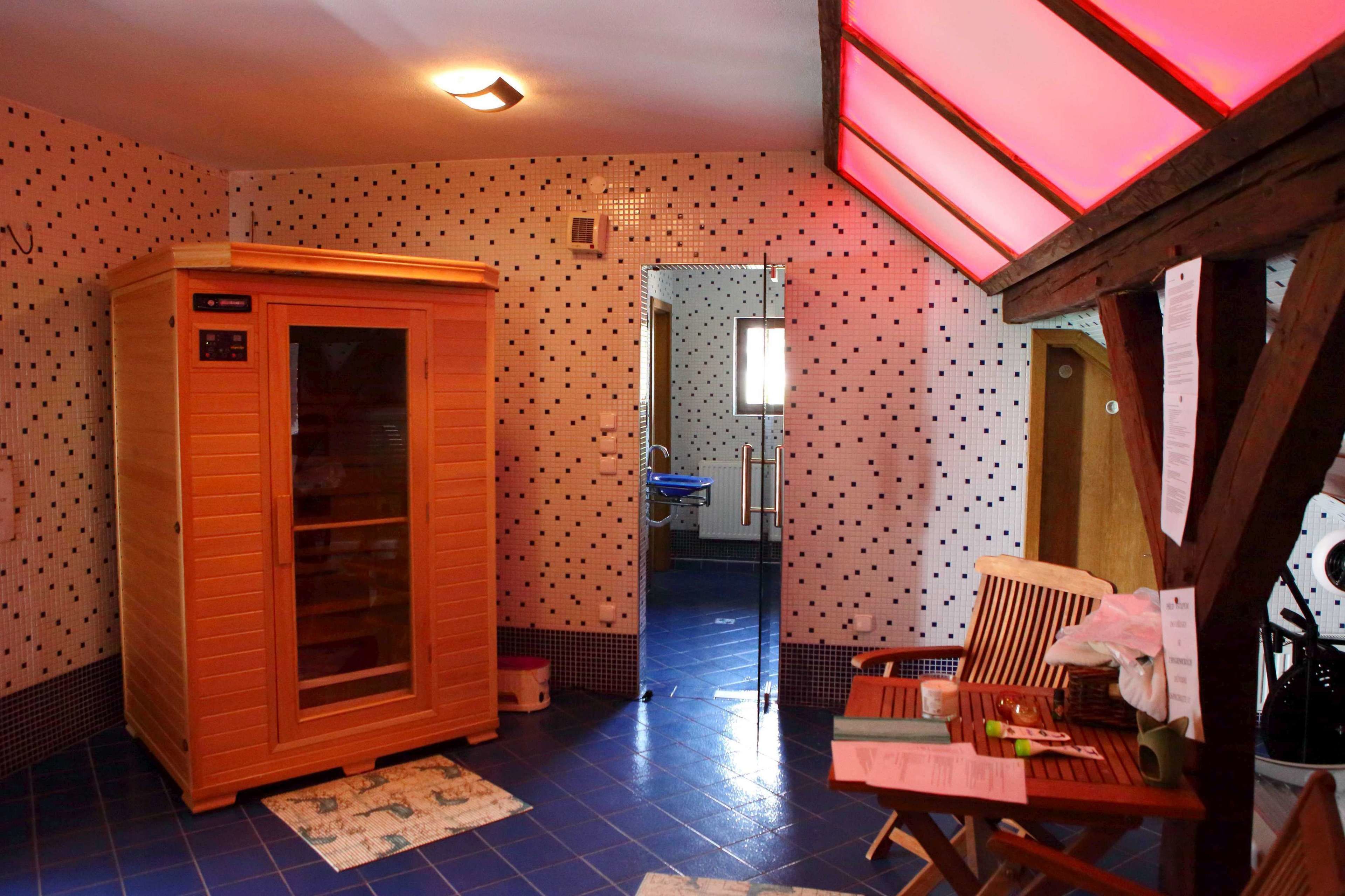 Quarto com sauna, armário de madeira, espelho, pequena mesa com objetos e uma cadeira.