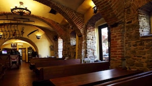 Um interior com paredes de pedra, bancos de madeira e um candelabro.