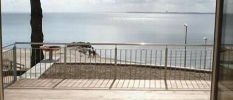 Um deck de madeira com grade de metal, com vista para a água.