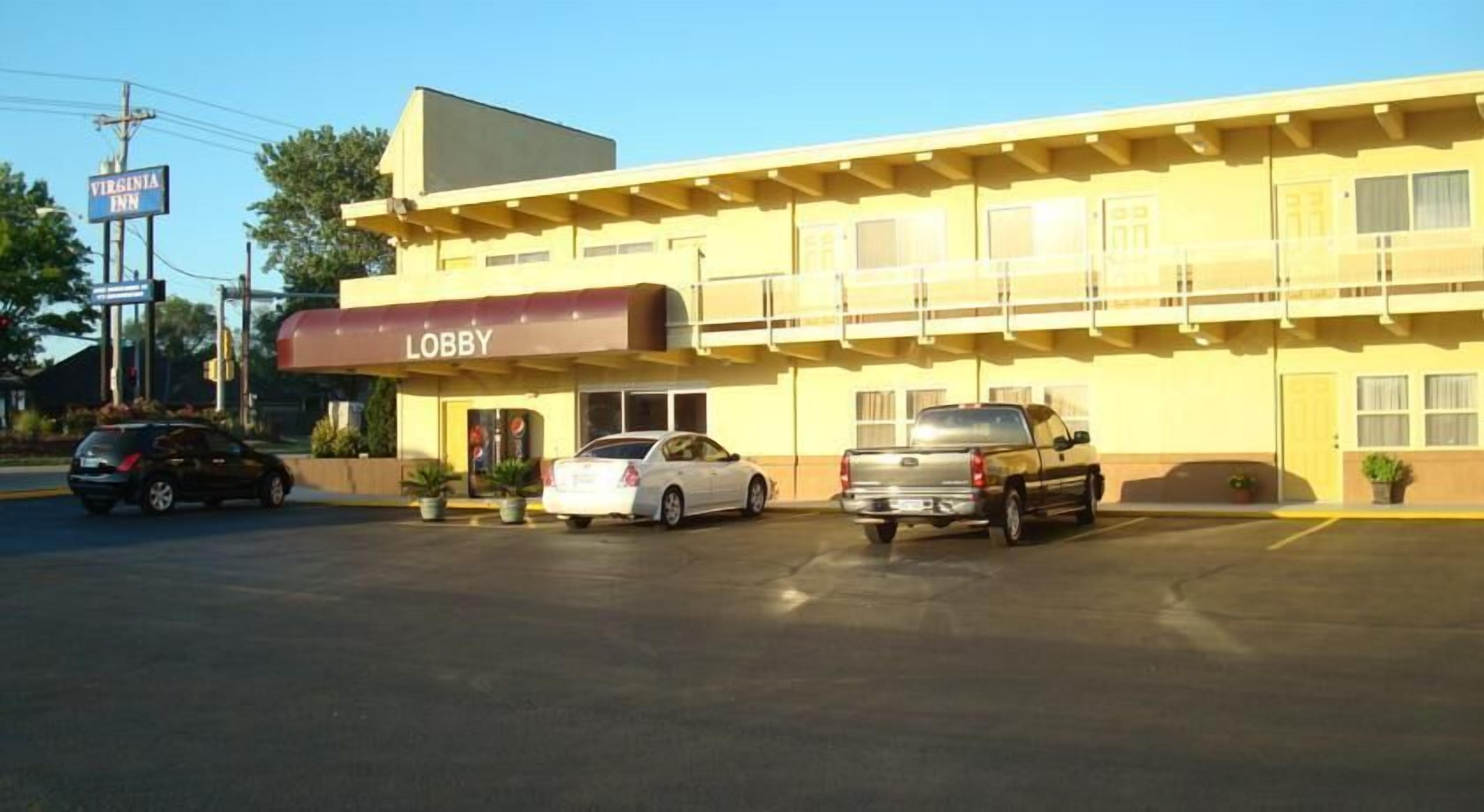 Uma hospedaria na Virgínia com entrada para o hall, um estacionamento e um edifício amarelo com várias janelas.