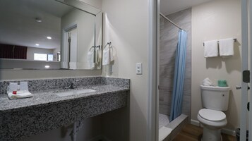 Um banheiro moderno com bancada de granito, box de vidro e vaso sanitário.