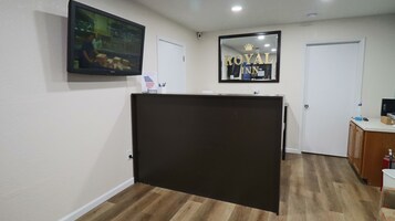 Uma área de recepção de hotel com uma divisória escura, uma TV de tela plana e uma placa para o Royal Inn.