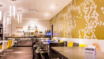 Restaurante moderno com área de bar, mesas e um painel decorativo.