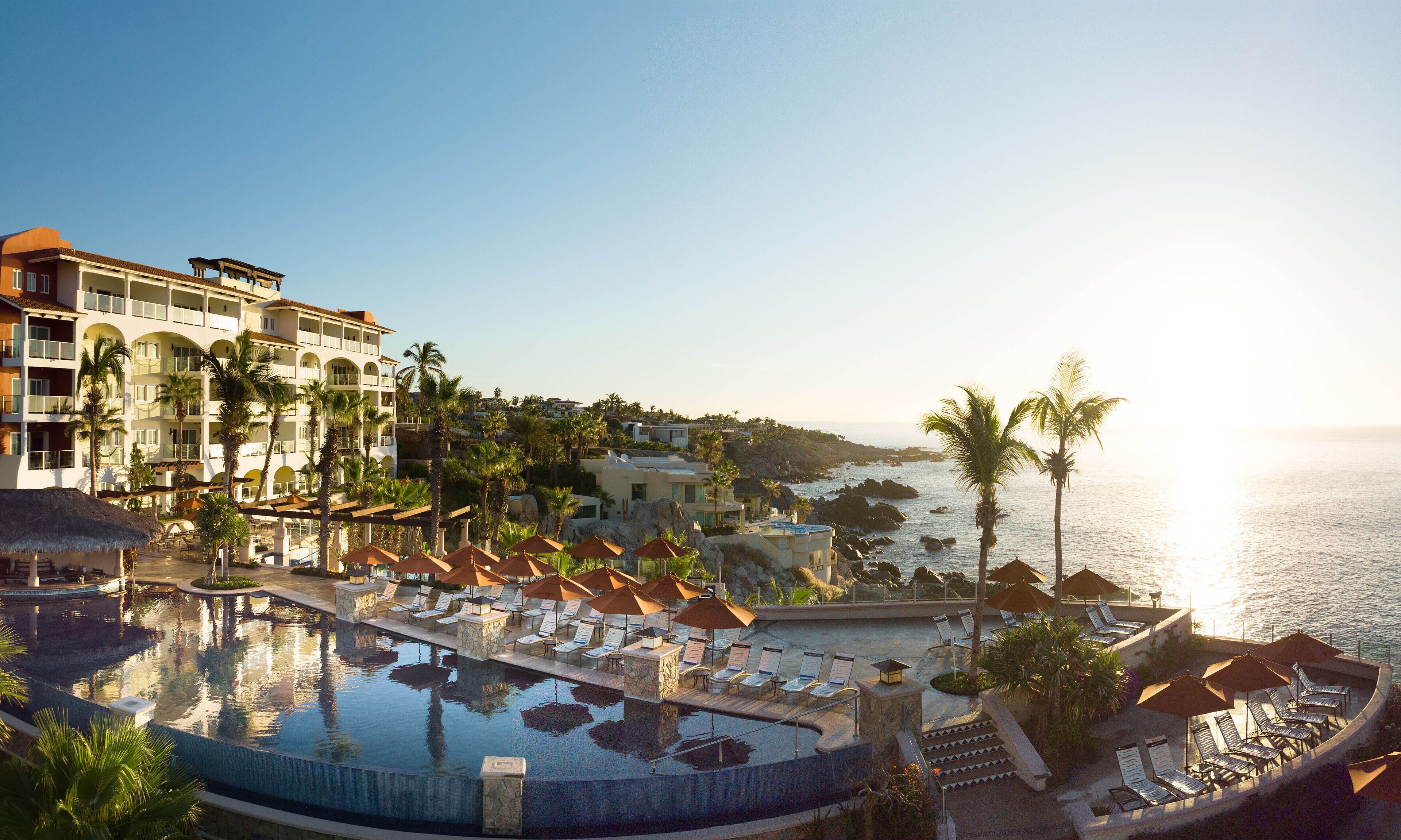 Um resort com piscina, espreguiçadeiras e vista para o oceano.
