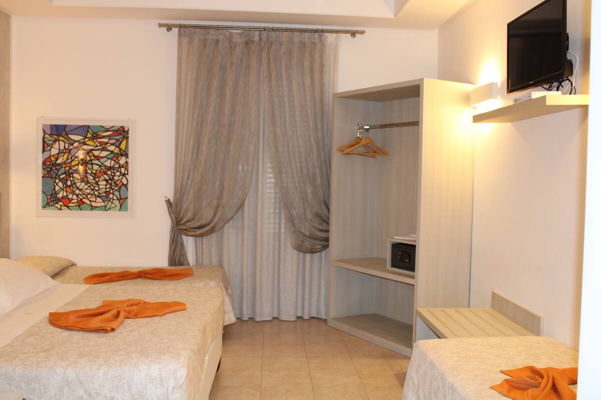 Quarto de hotel com duas camas, televisão, um quadro e um guarda-roupa.