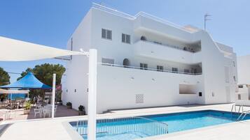 Um edifício moderno com piscina, área de estar ao ar livre e céu azul vibrante.