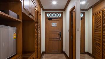Corredor com portas de madeira, um refrigerador e piso revestido de azulejos.