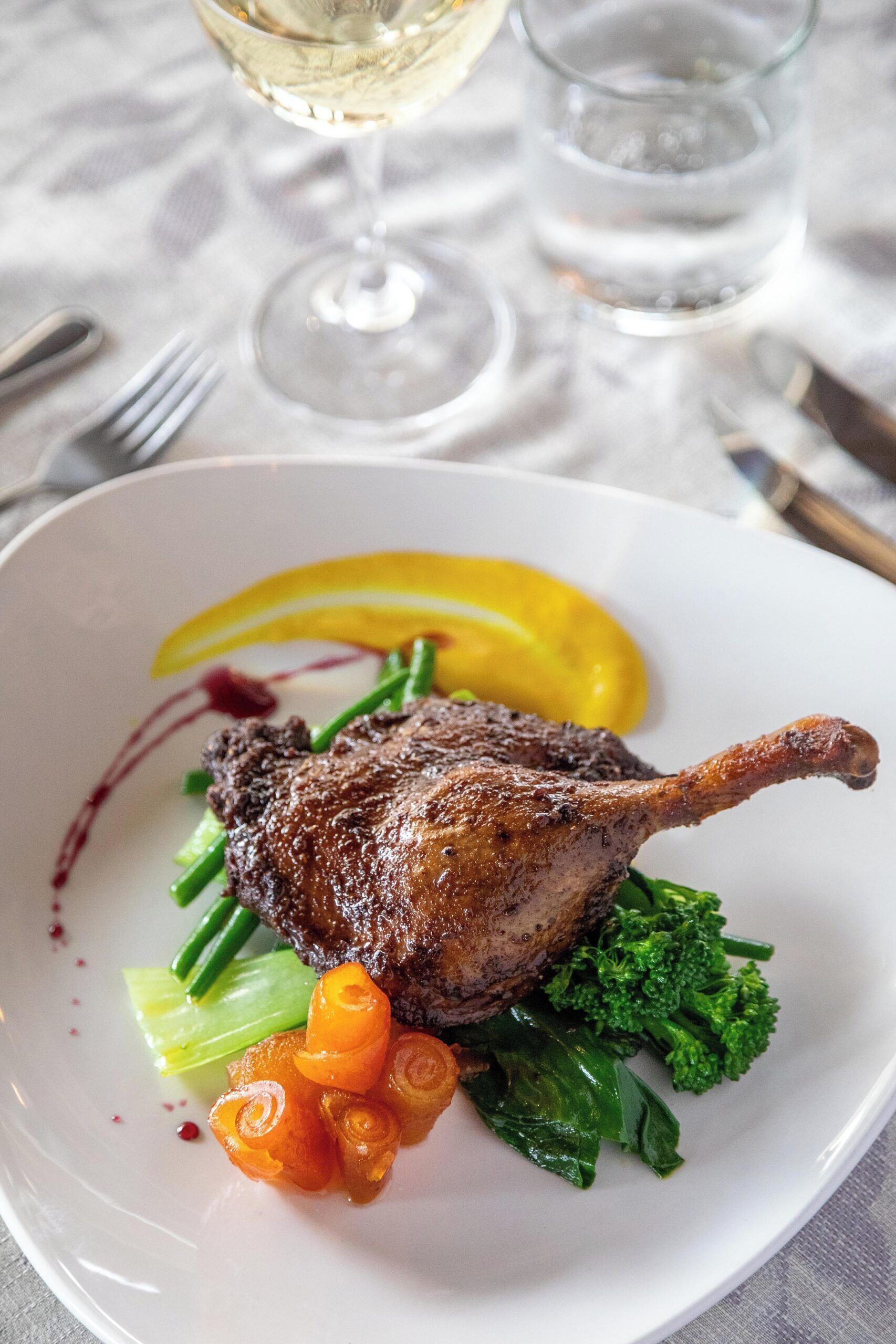 Prato com pato, legumes e uma fatia de limão.