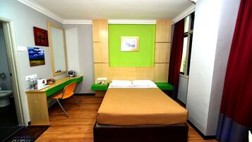 Quarto de hotel com cama, escrivaninha com cadeira, pia e janela com cortinas.