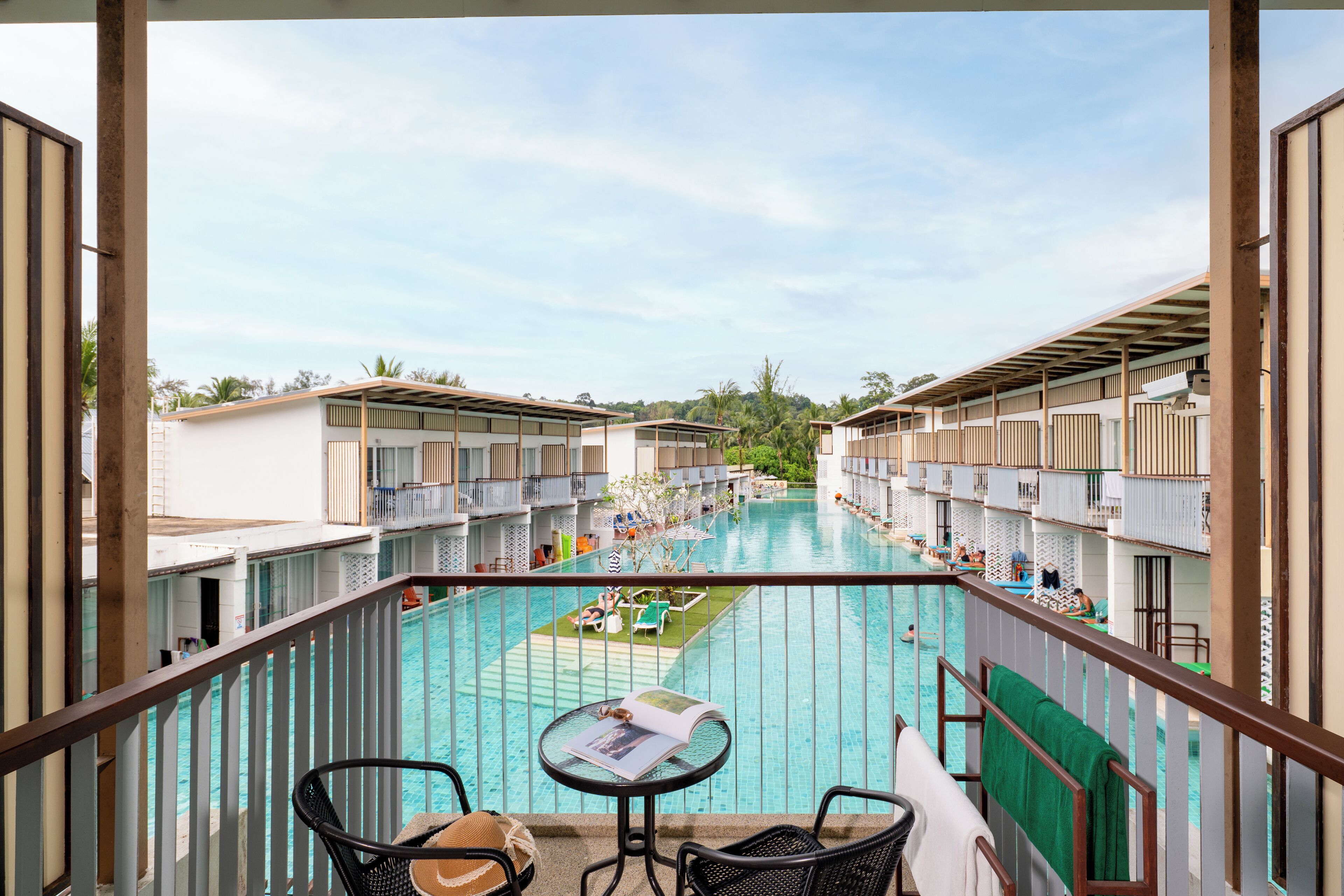 Varanda de hotel com piscina, apresentando várias varandas, uma mesa pequena e cadeiras.