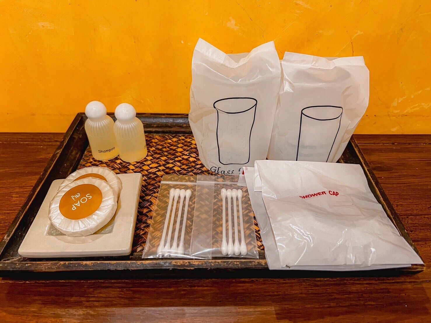 Uma bandeja com artigos de higiene, incluindo garrafas de shampoo, um sabonete, cotonetes e uma necessaire de banho.