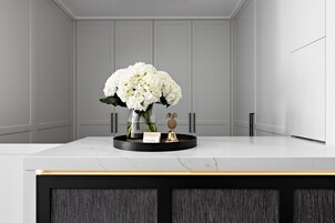 Bancada de mármore com um vaso de flores brancas, um pequeno cartão e um enfeite em formato de abacaxi.