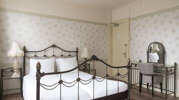 Um quarto com uma cama de dossel, uma escrivaninha com cadeira e um espelho.