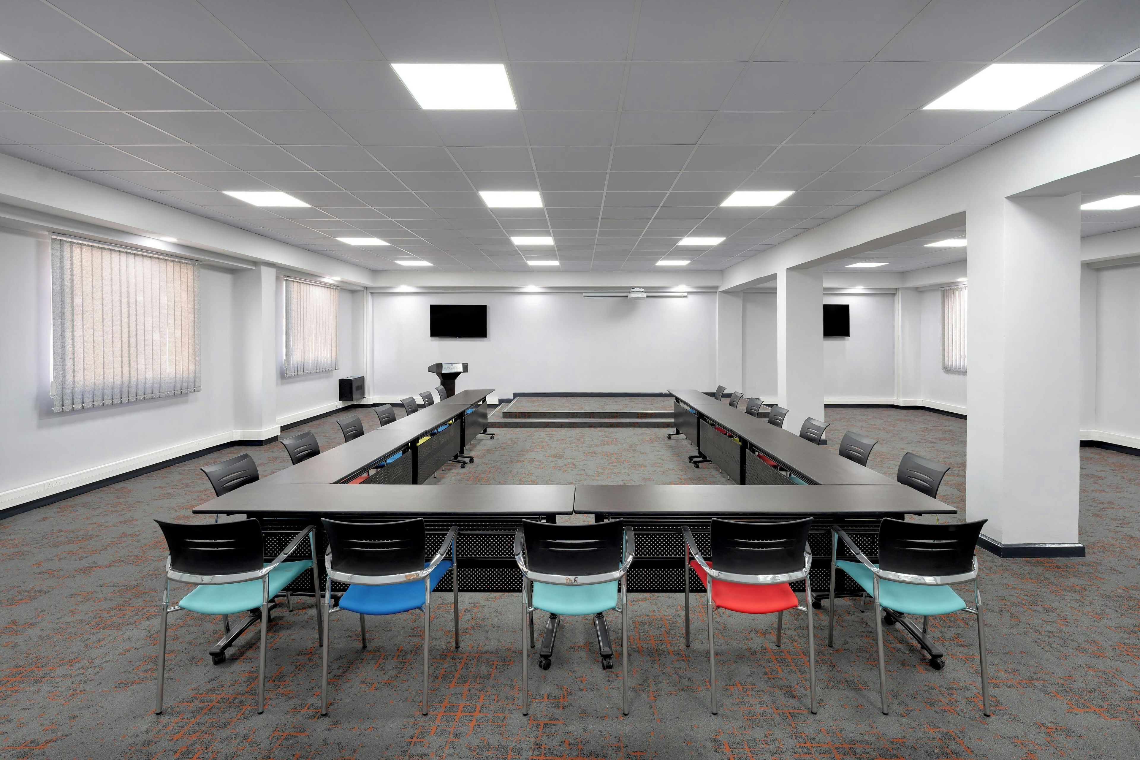 Uma sala de conferências com uma mesa comprida, cadeiras e uma tela de projeção.