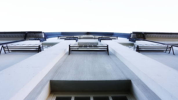 Terraço no telhado com várias grades de metal preto, um banco preto central e uma grande janela na frente.