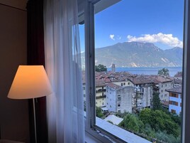 Quarto com vista para uma cidade costeira, uma montanha e um farol.
