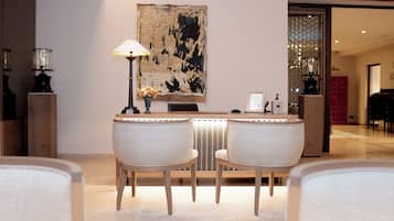 Uma mesa de recepção com duas cadeiras, um abajur e um grande quadro abstrato na parede.