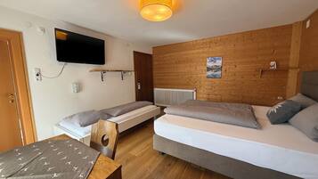 Quarto com cama, um banco, uma televisão e parede de madeira.