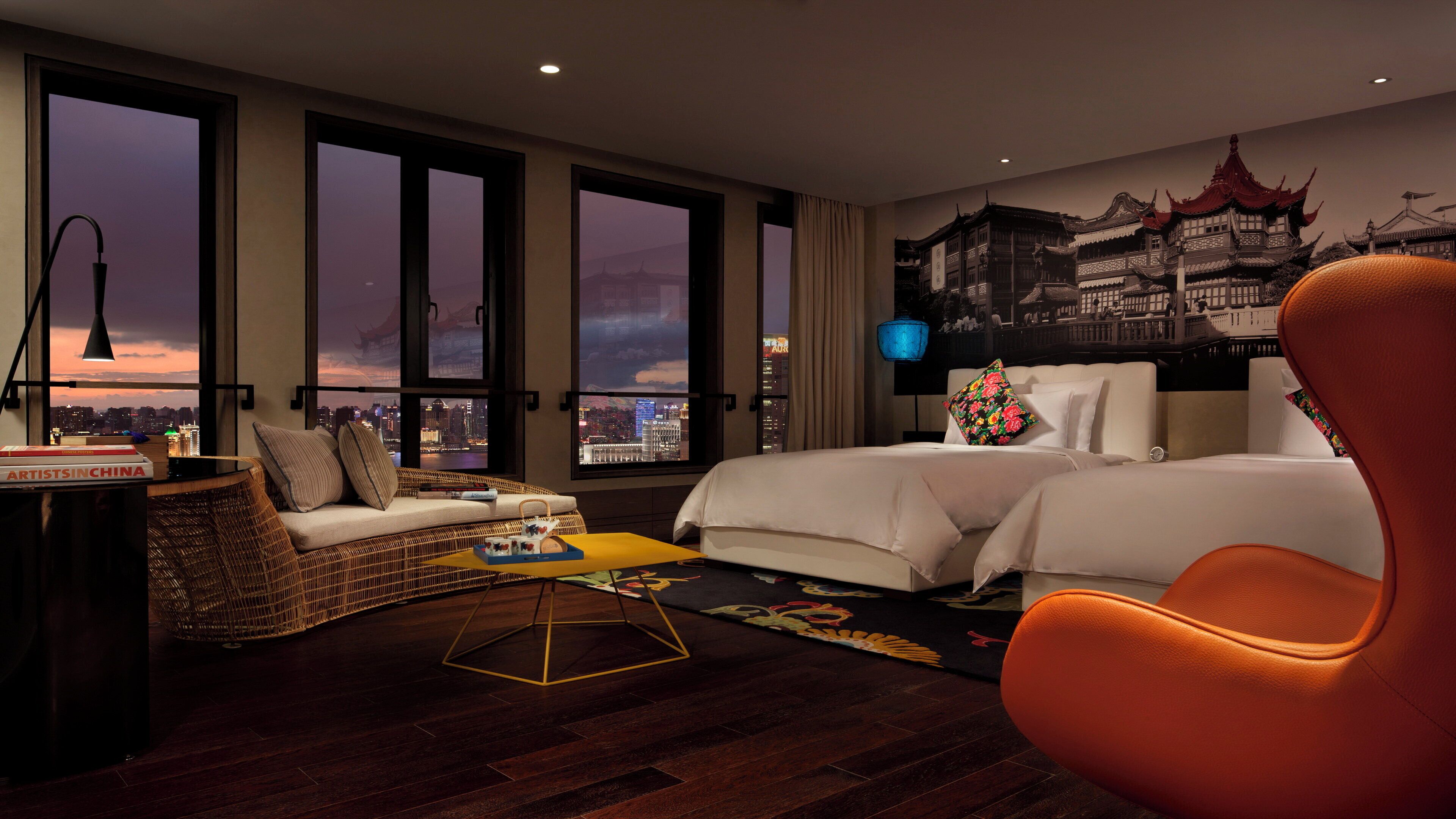 Quarto de hotel com vista para a cidade, um sofá, duas camas, uma mesa de centro e uma cadeira.