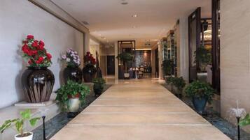 Corredor de hotel com plantas em vasos e piso de mármore.