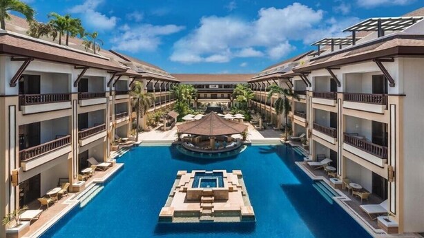 Um hotel com piscina central, várias varandas e áreas de estar ao ar livre.