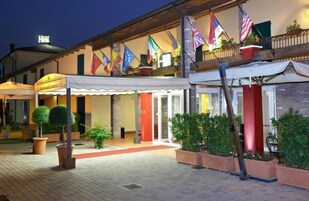 Um hotel com área externa coberta, plantas em vasos e várias bandeiras.