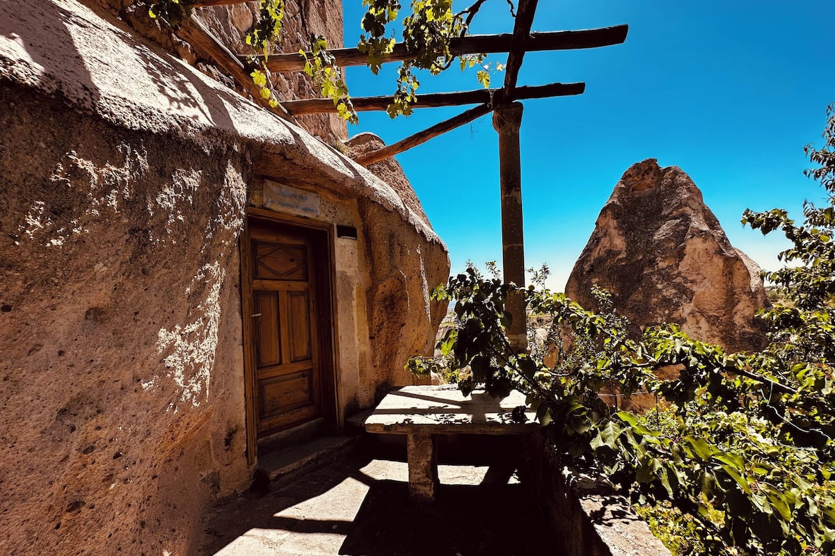 Um edifício rústico de pedra com porta de madeira e estrutura em cruz.
