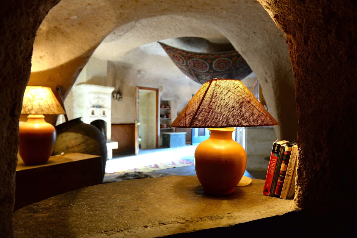 Um arco de pedra com uma lâmpada e livros sobre uma mesa.