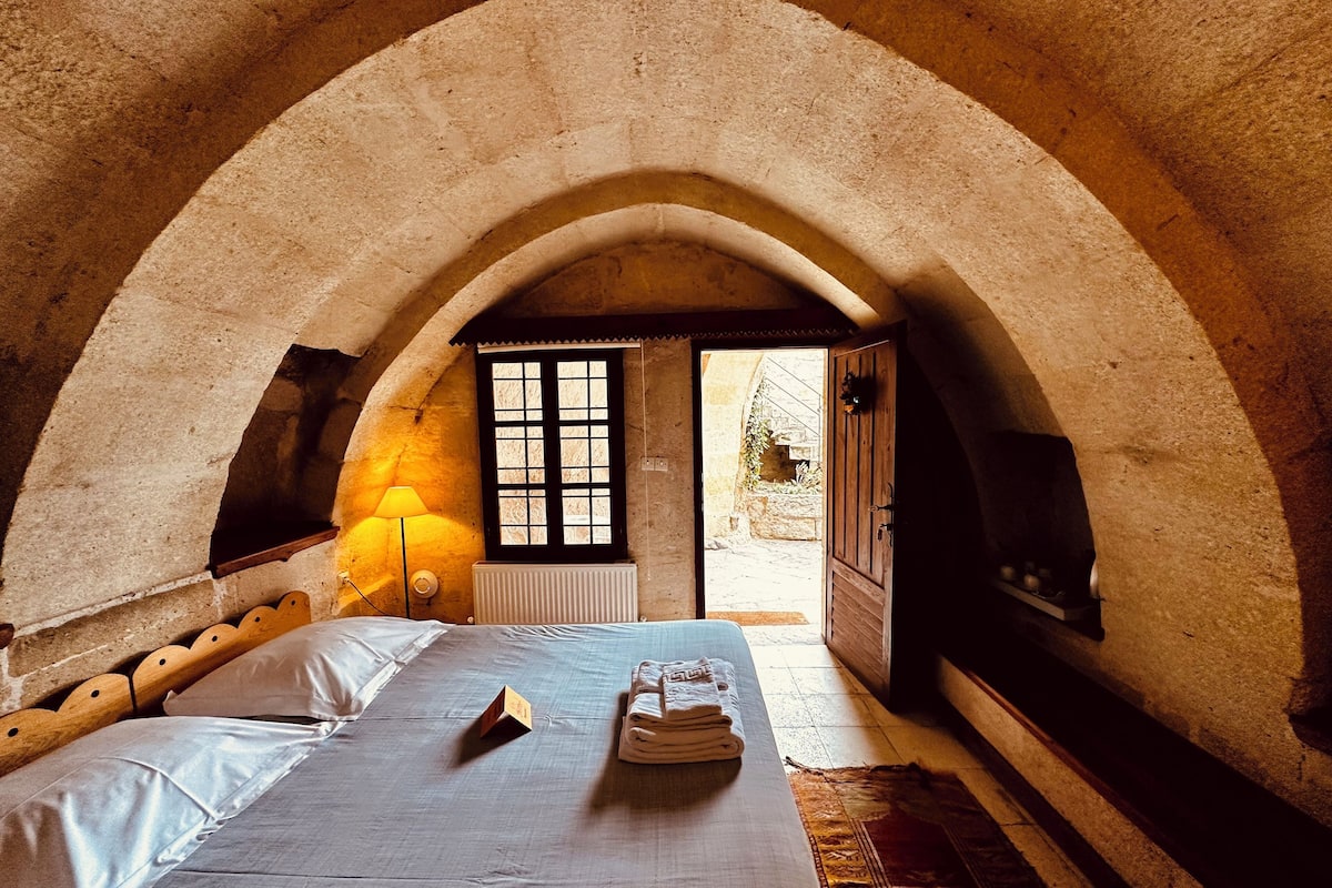 Um quarto acolhedor com uma cama, um abajur e vista por uma porta aberta.