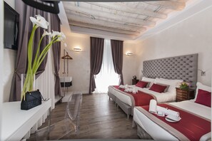 Quarto de hotel com duas camas, uma escrivaninha e uma cadeira. Cortinas, televisão e teto com vigas aparentes.