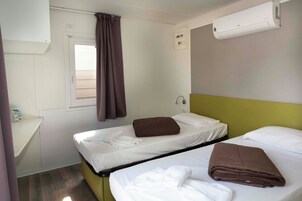 Quarto de hotel com duas camas, uma escrivaninha e um ar condicionado.