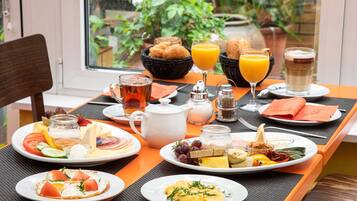 Uma mesa de café da manhã com diversos pratos, incluindo torradas, ovos e frutas, acompanhados de bebidas e acompanhamentos.