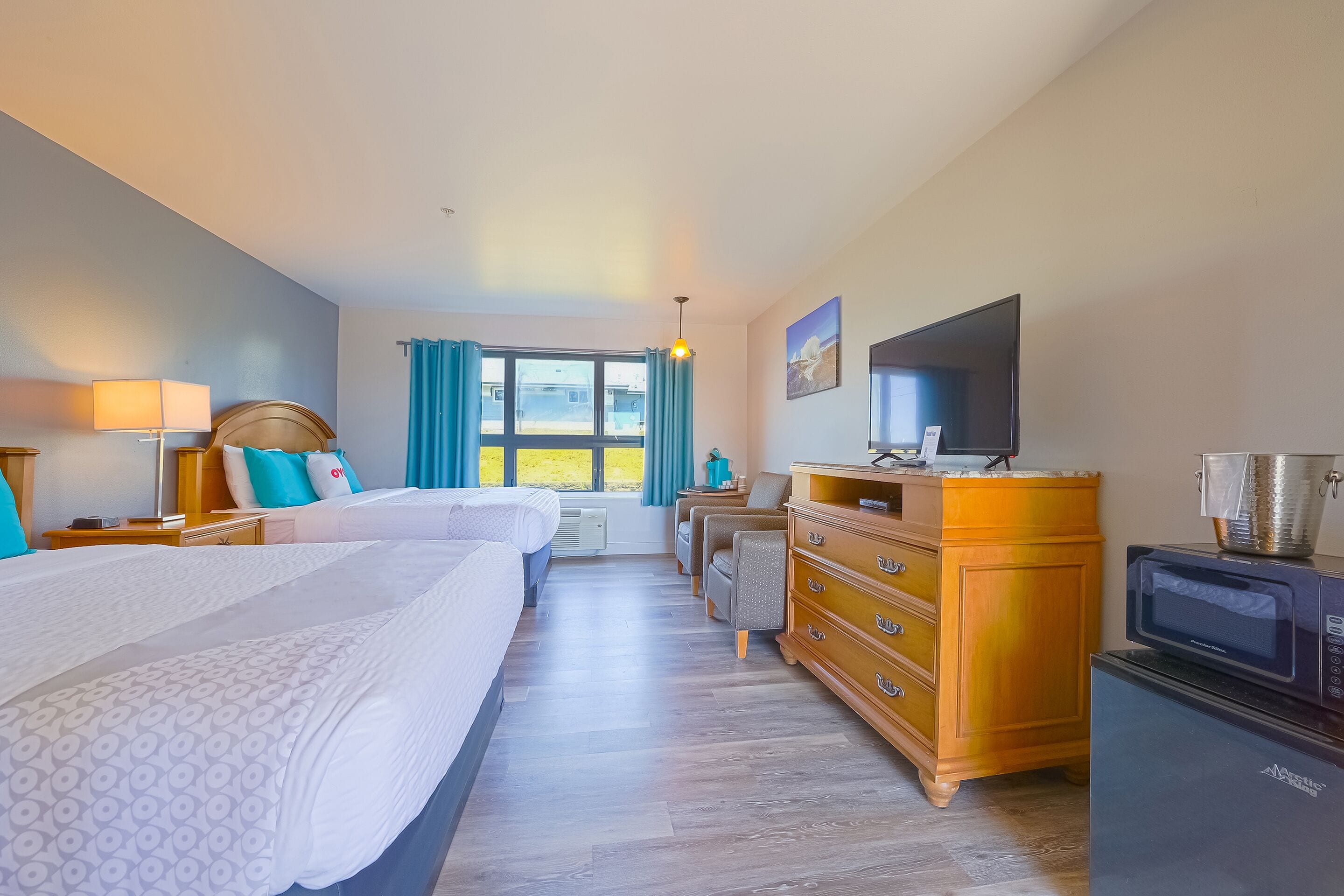 Quarto de hotel com duas camas, televisão, penteadeira e micro-ondas.