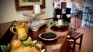 Uma área de refeições com um espaço para café, pratos decorativos e um jarro.