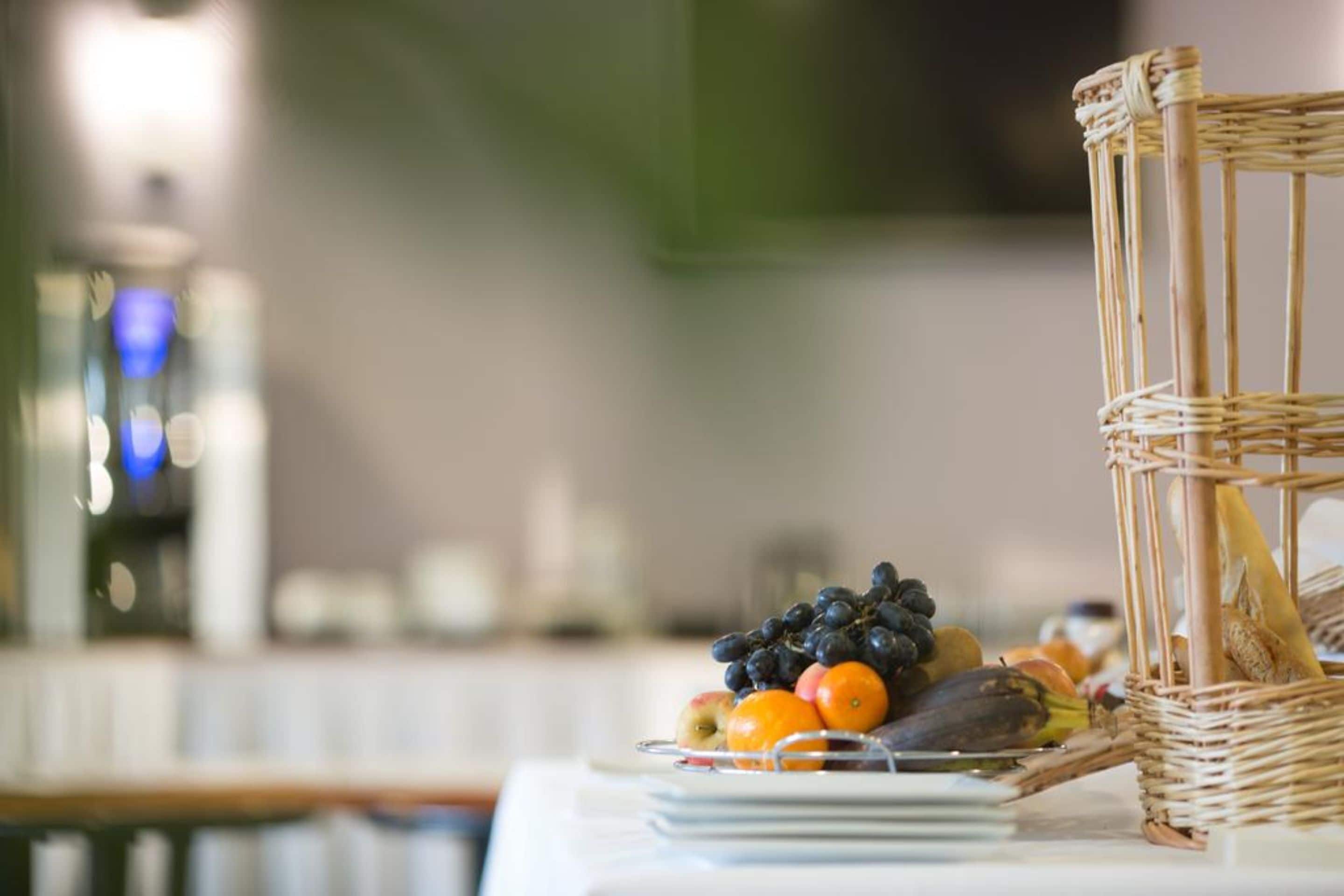 Uma cesta de vime com frutas sobre uma mesa, com fundo desfocado.