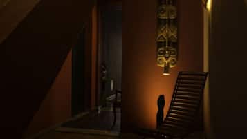 Um corredor com pouca luz, um banco e um objeto decorativo na parede.