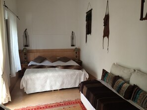 Quarto com cama, sofá, tapete estampado e decorações nas paredes.