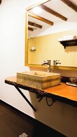 Casa de banho com toucador de madeira, pia e espelho.
