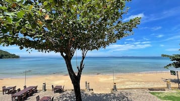 Na praia, praia de areia branca, espreguiçadeiras, guarda-sóis de praia