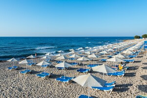 Na praia, espreguiçadeiras, guarda-sóis, toalhas de praia 