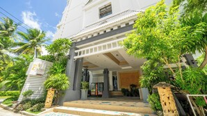 Um edifício moderno com fachada branca, entrada coberta e placa indicando local para maiores de 21 anos.